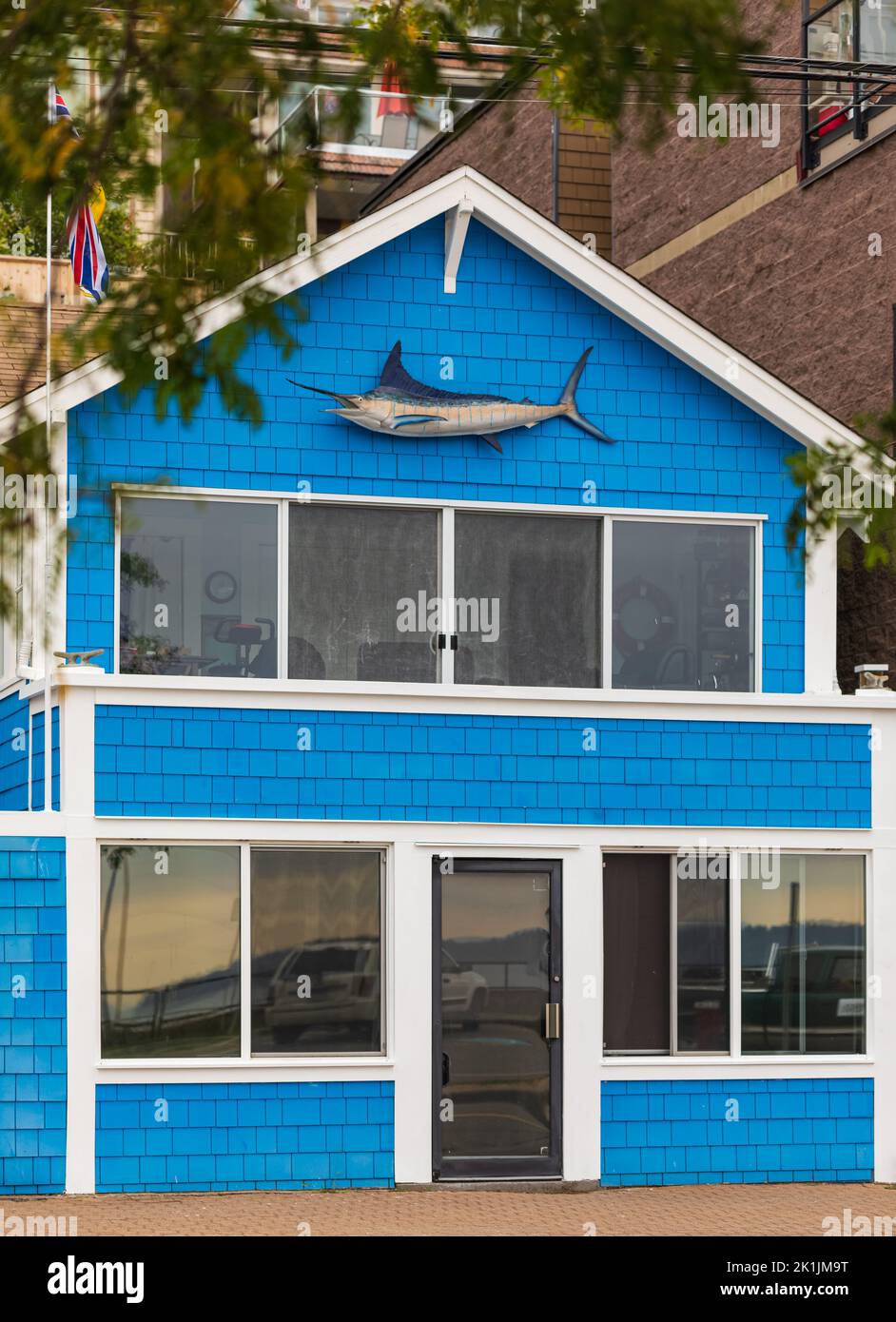 Bright blue house in sunlght decorated with fish on the top. Facade of ...