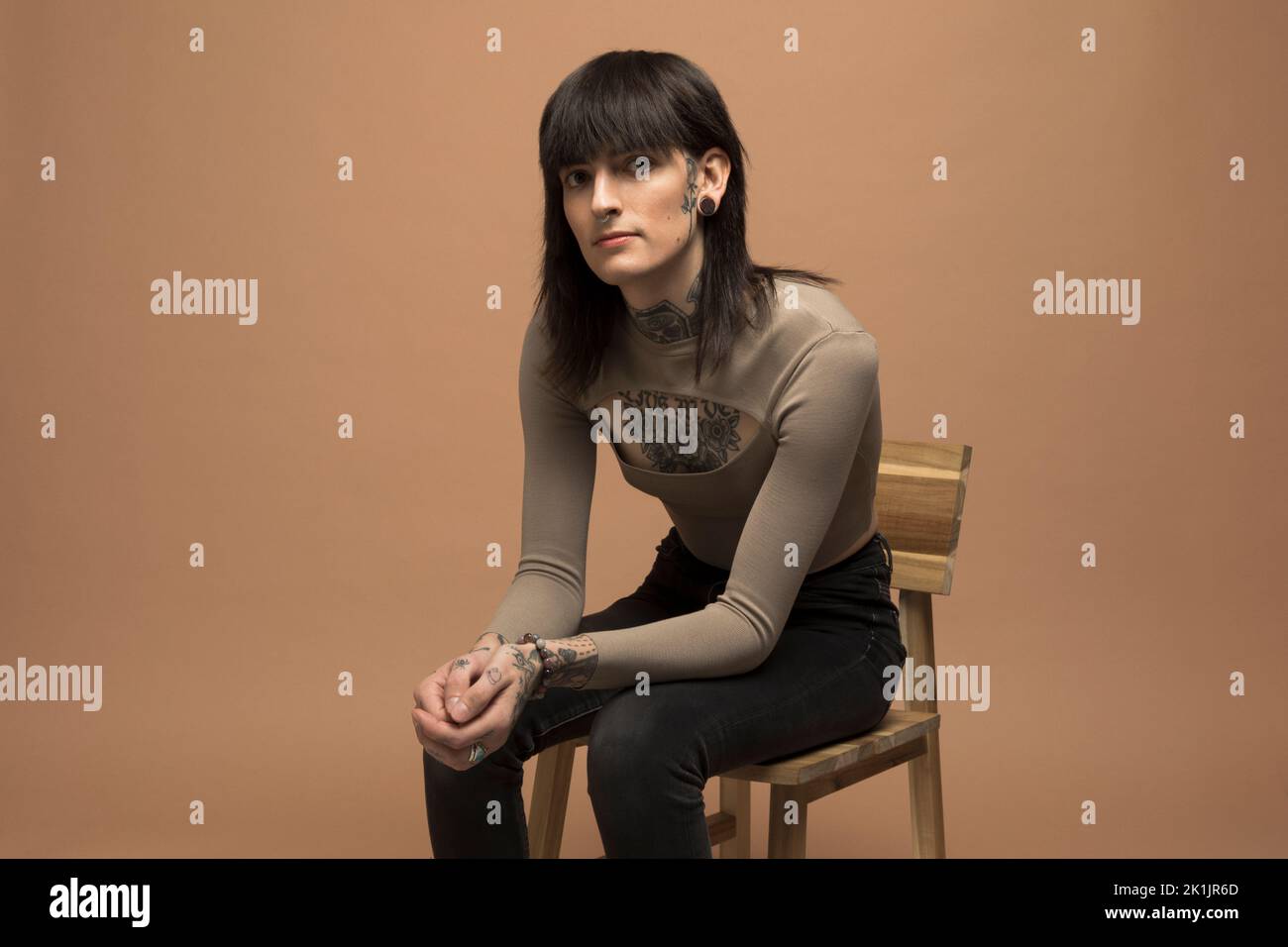 Portrait of confident transgender woman with tattoos in chair Stock ...