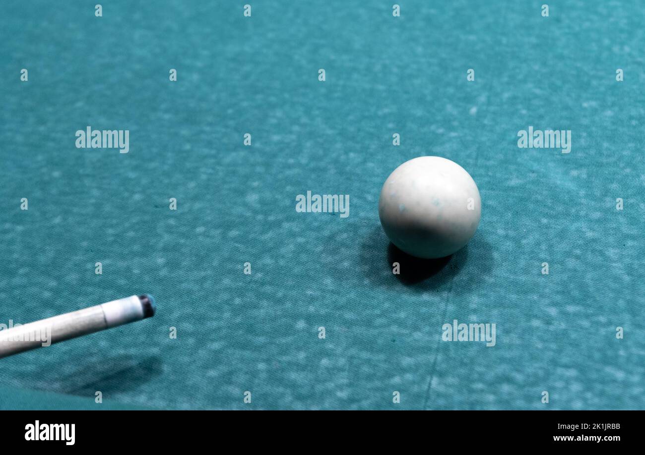 Cue ball on a worn out old pool table. A game of pool with used ...