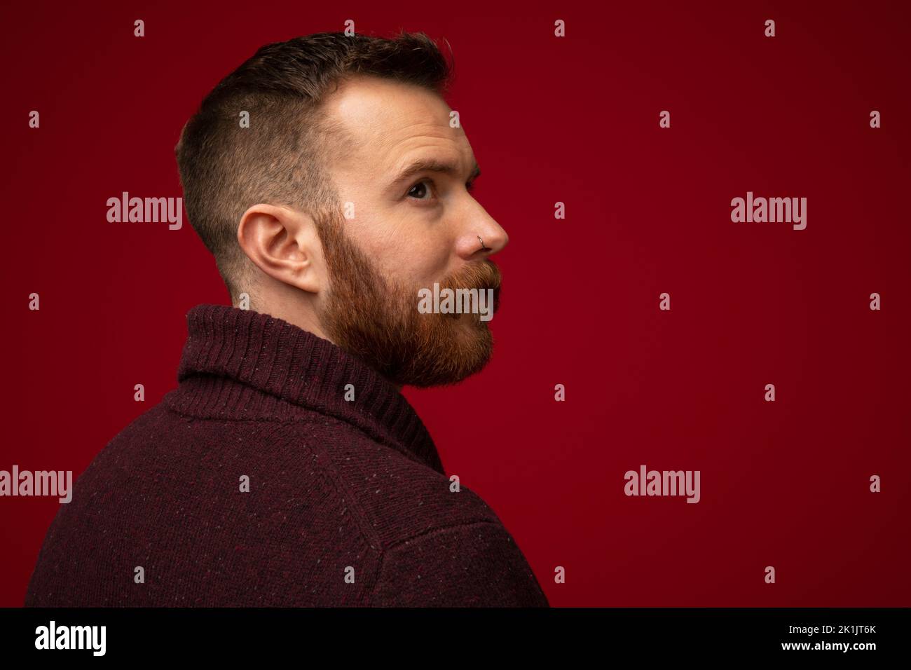Portrait of thoughtful transgender man with red beard and nose ring ...