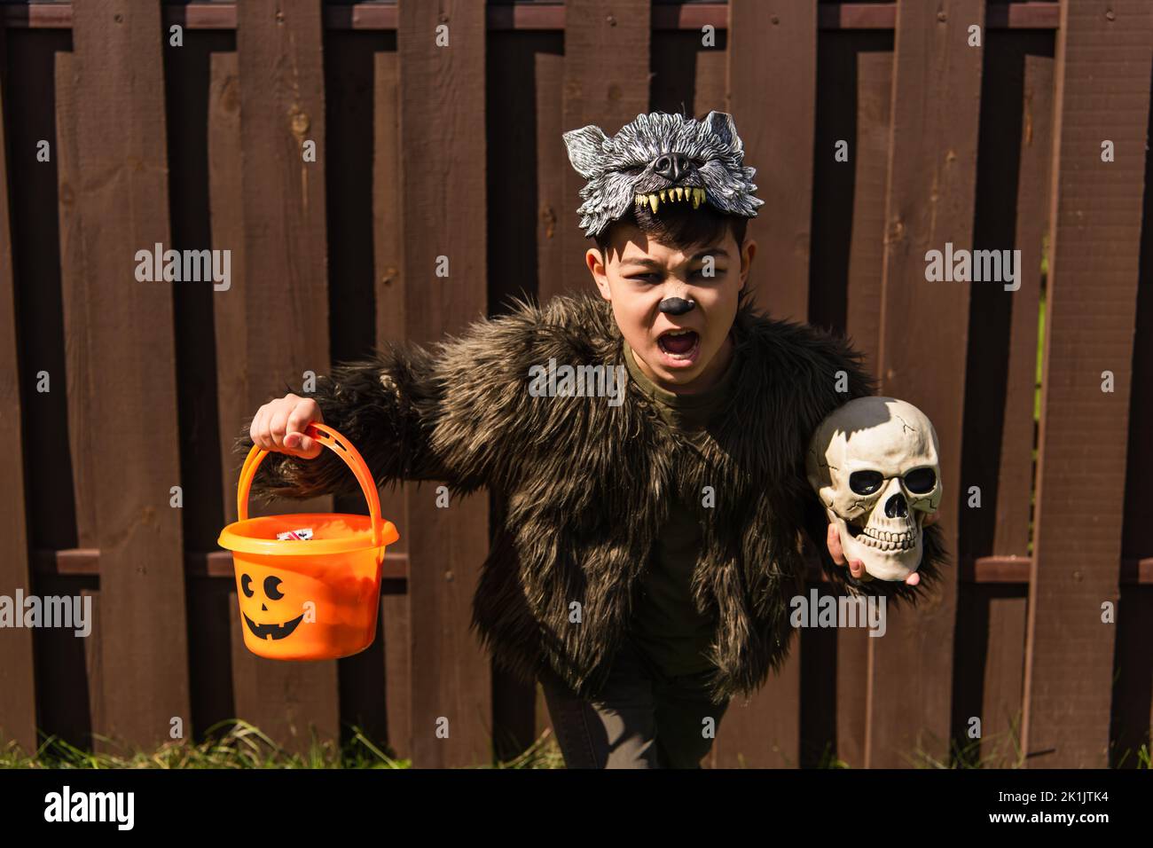 asian boy in werewolf costume running with skull and trick or treat ...