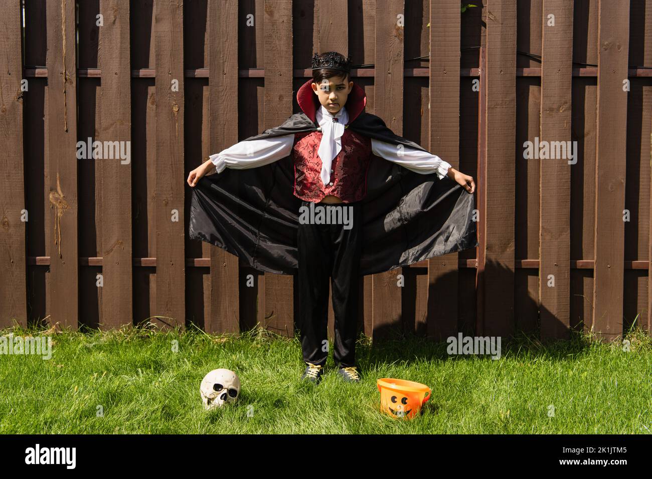 full length of asian boy in vampire king costume holding cape near ...