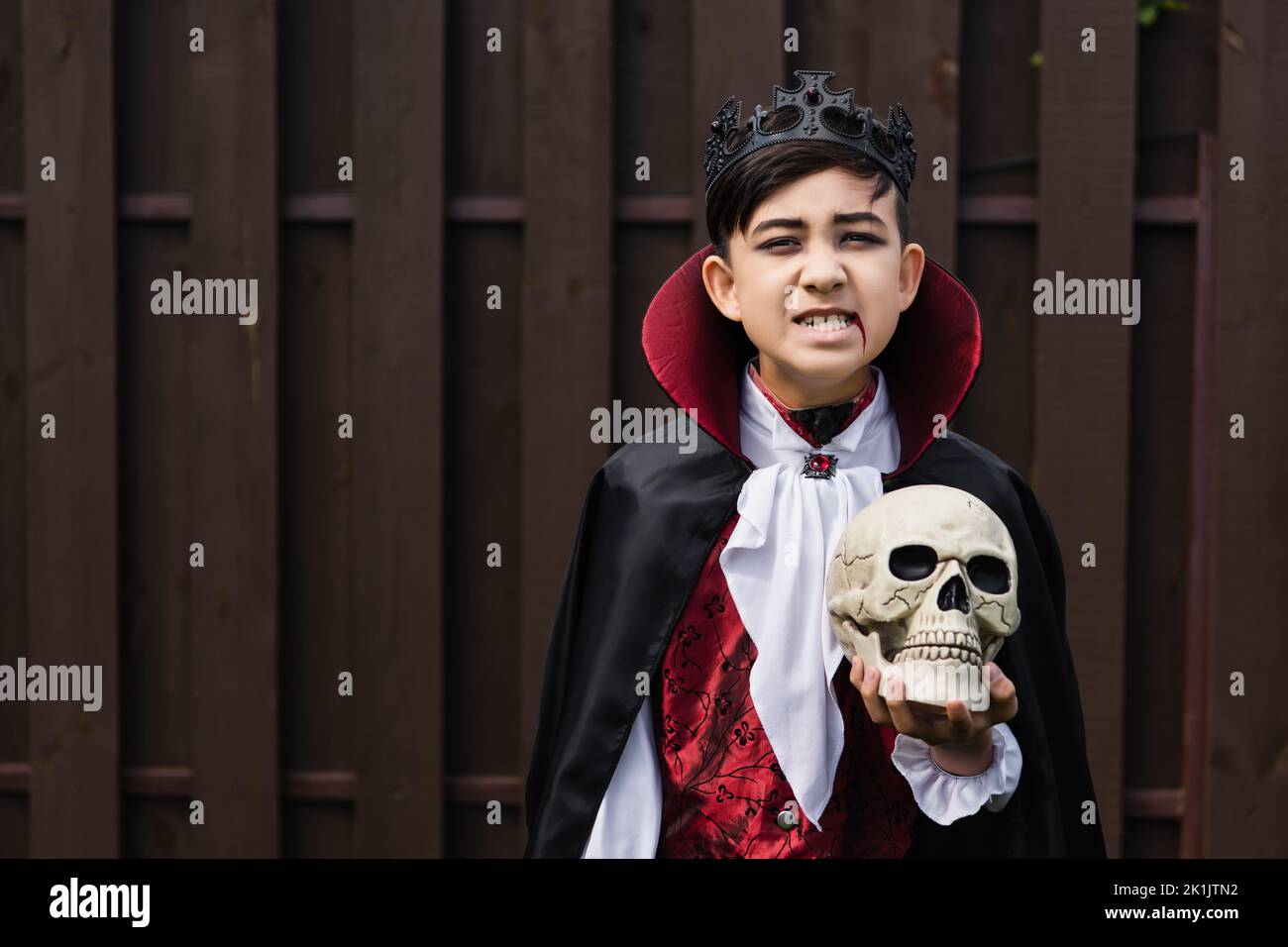 asian boy in vampire king costume growling while holding skull and ...