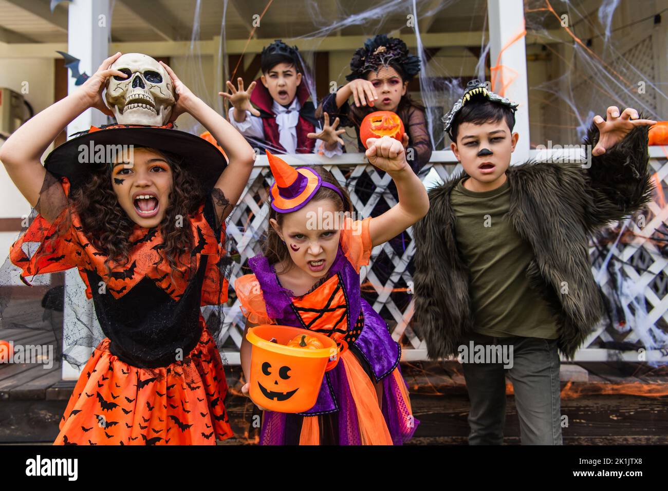 Preteen multiethnic kids with bucket and skull grimacing at camera near ...