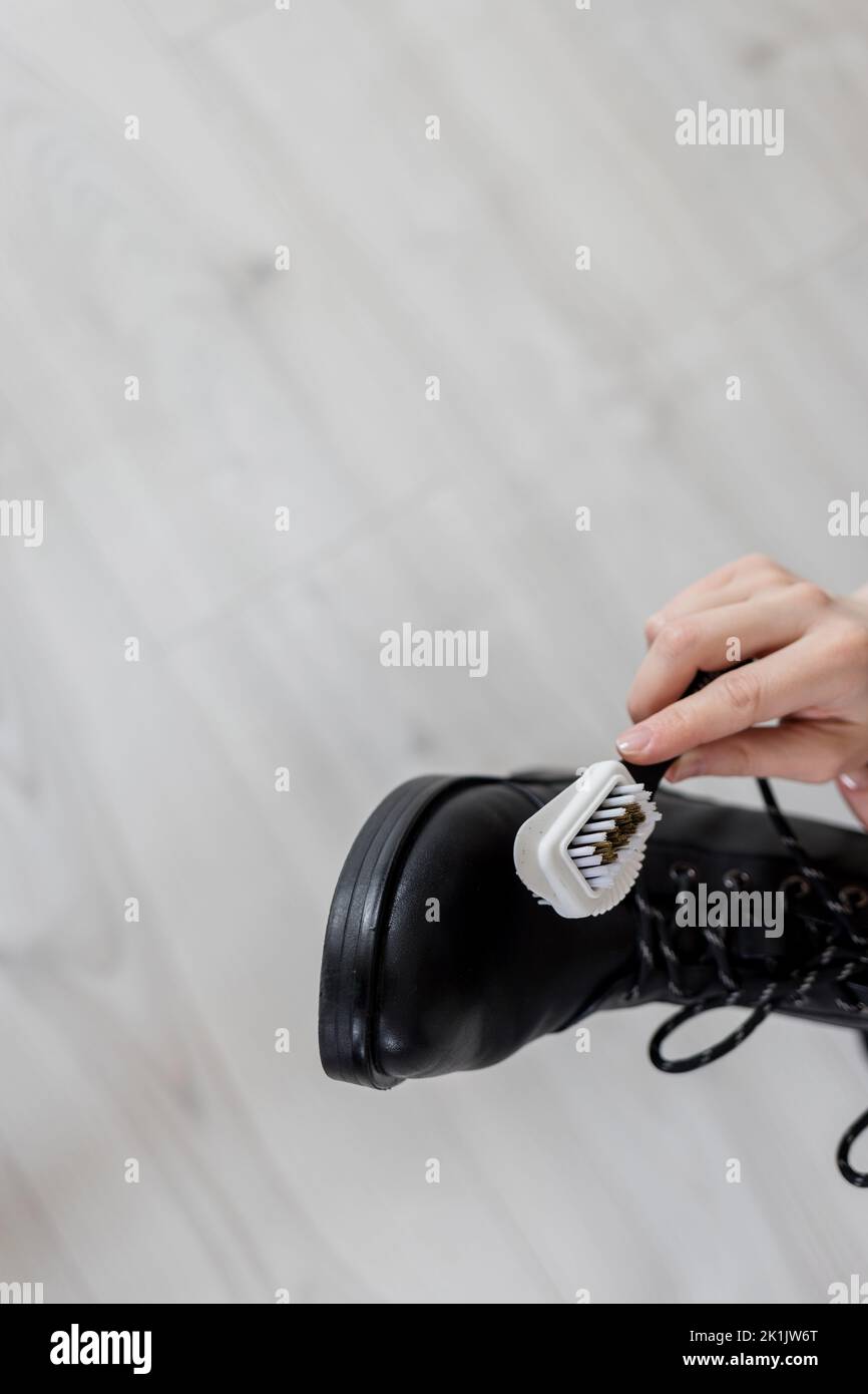 A person is cleaning leather casual boots with brush. Shoe shine and ...