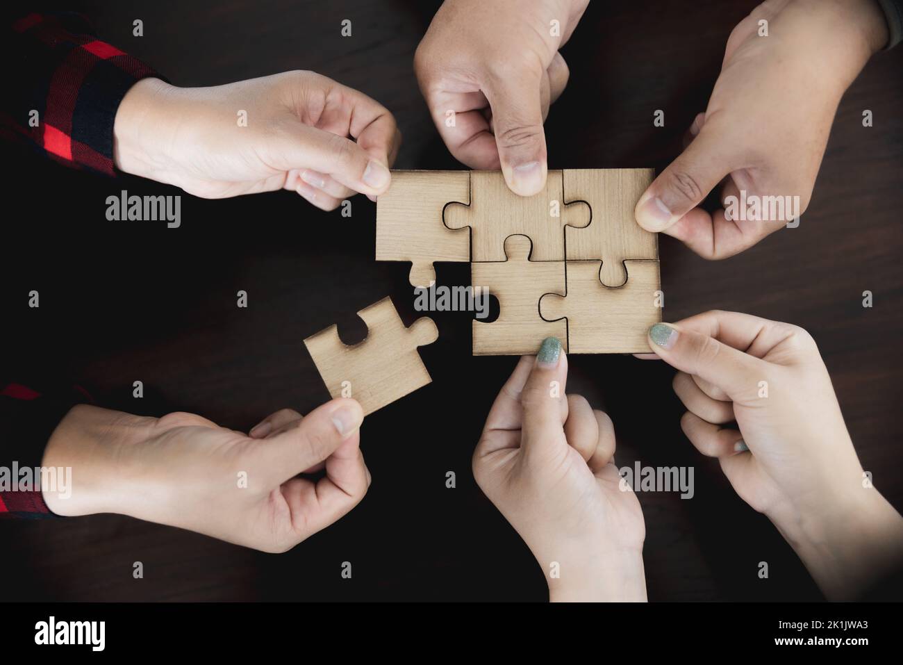 Hands of diverse people assembling jigsaw puzzle, team put pieces ...