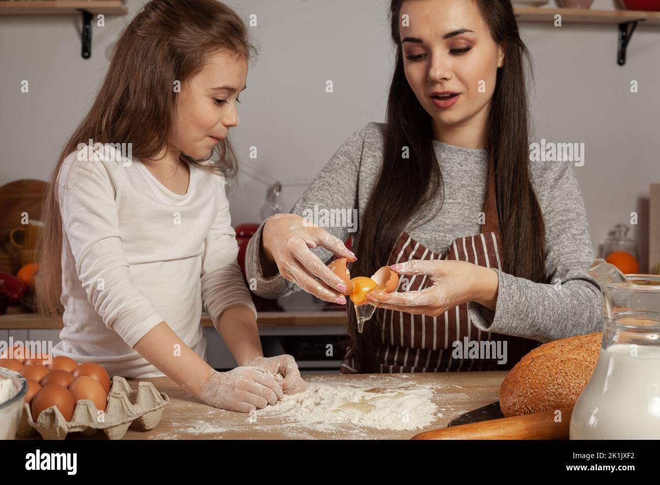 Mother and her daughter are baking a bread and having fun at the ...