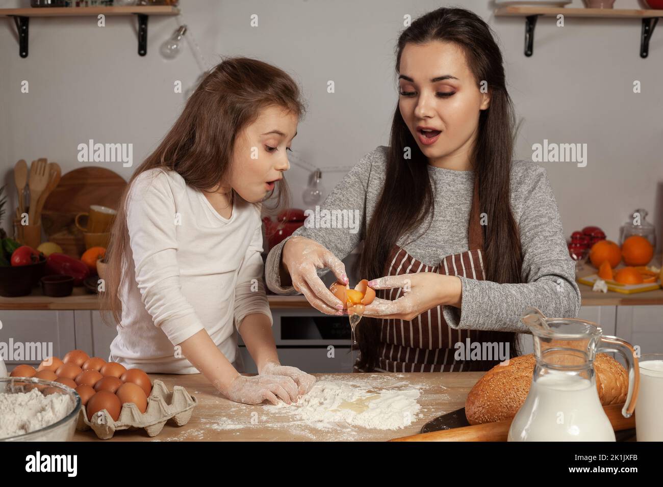 Mother and her daughter are baking a bread and having fun at the ...