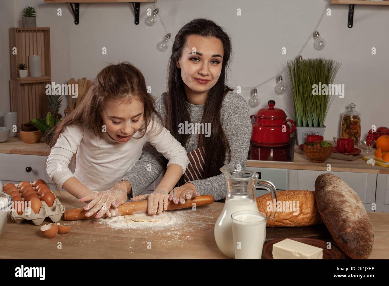 Mother and her daughter are baking a bread and having fun at the ...