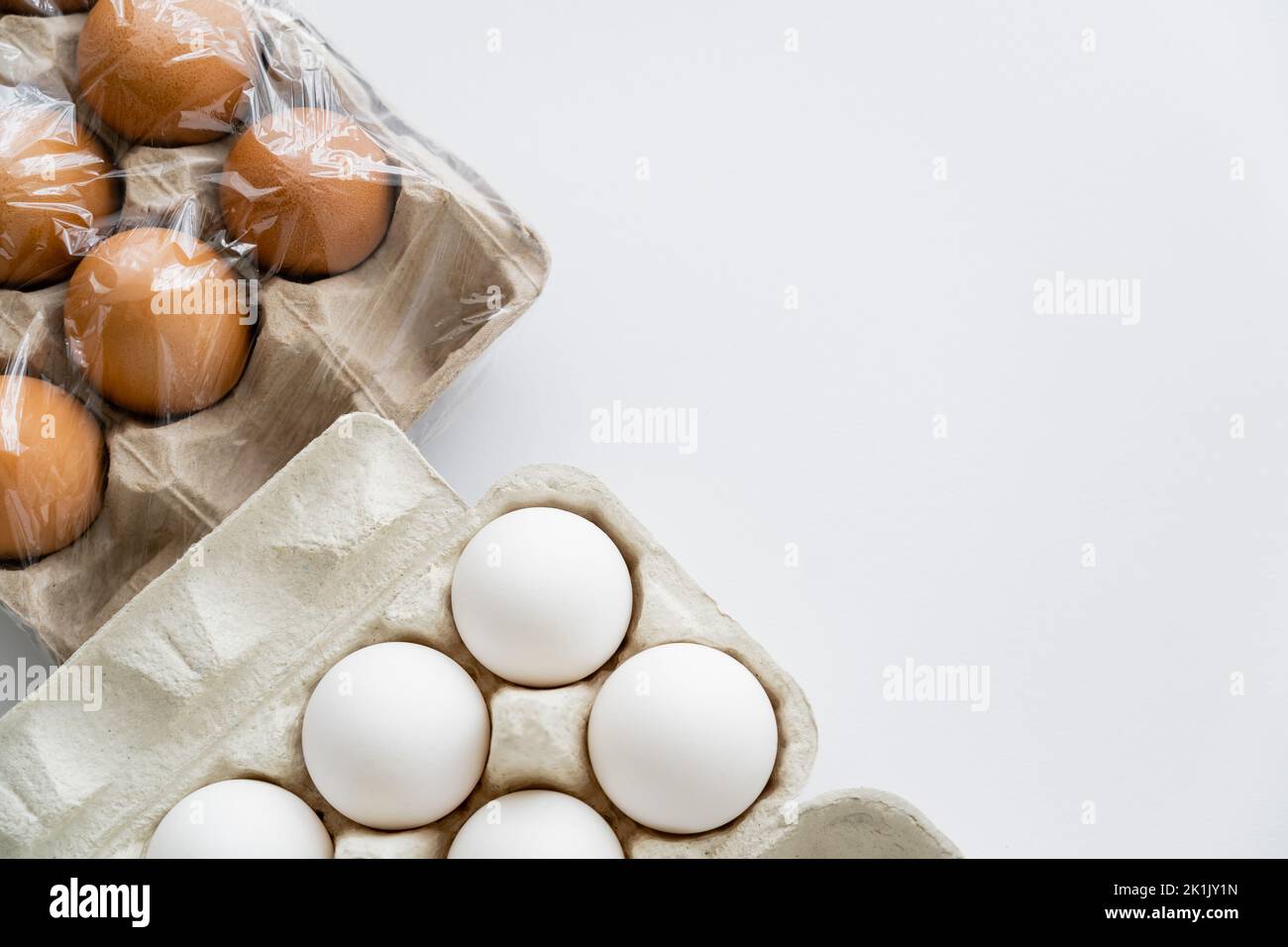 Top view of different eggs in carton boxes with cellophane on white ...