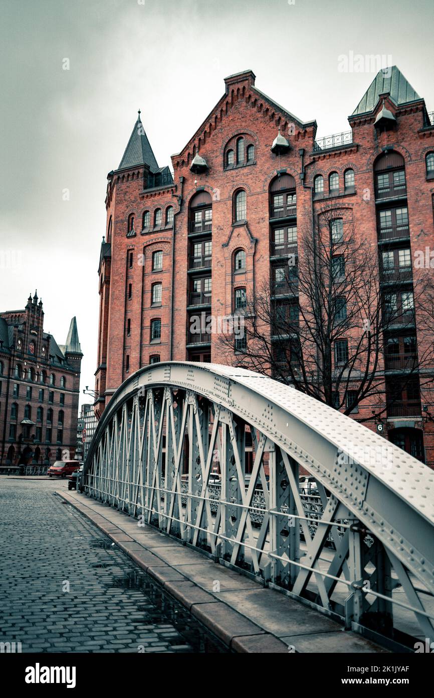 An arch bridge over Alster canals with the cobbled road with red brick ...