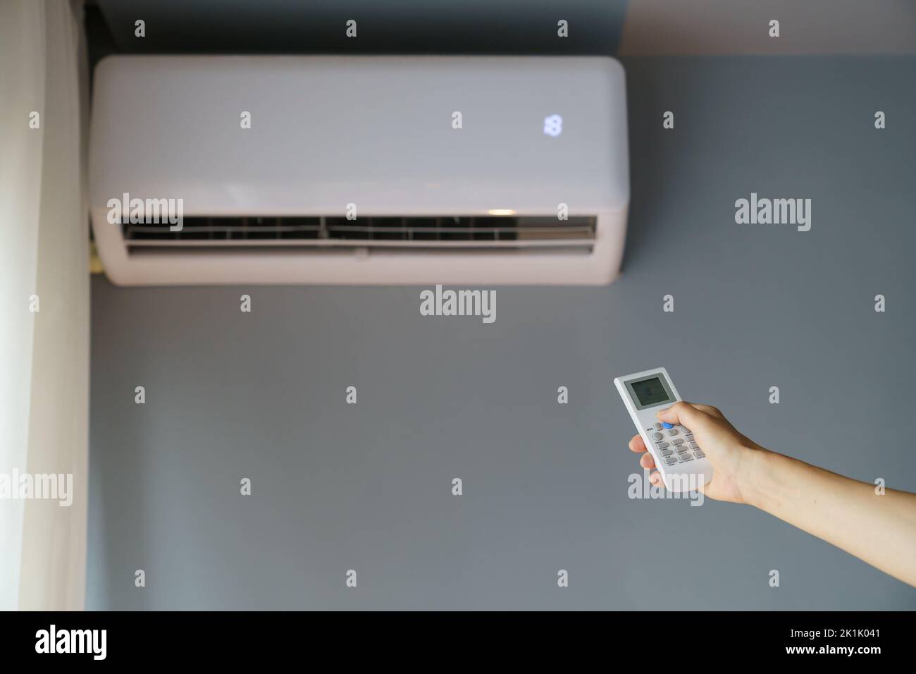Owner turns on air conditioner hanging on wall with remote control to ...