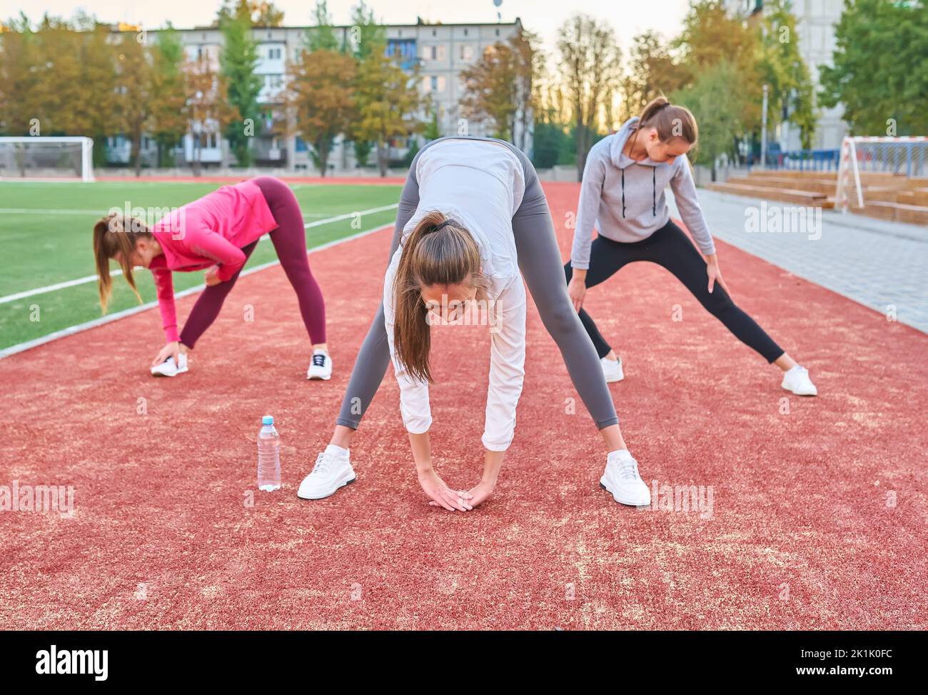 Three girls doing stretching exercises at the football stadium Stock ...