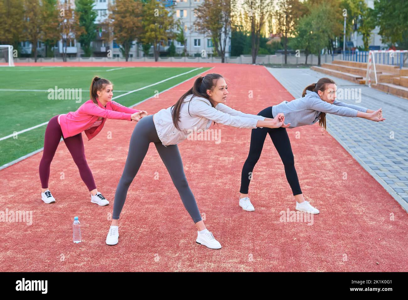 Three girls doing stretching exercises at the football stadium Stock ...