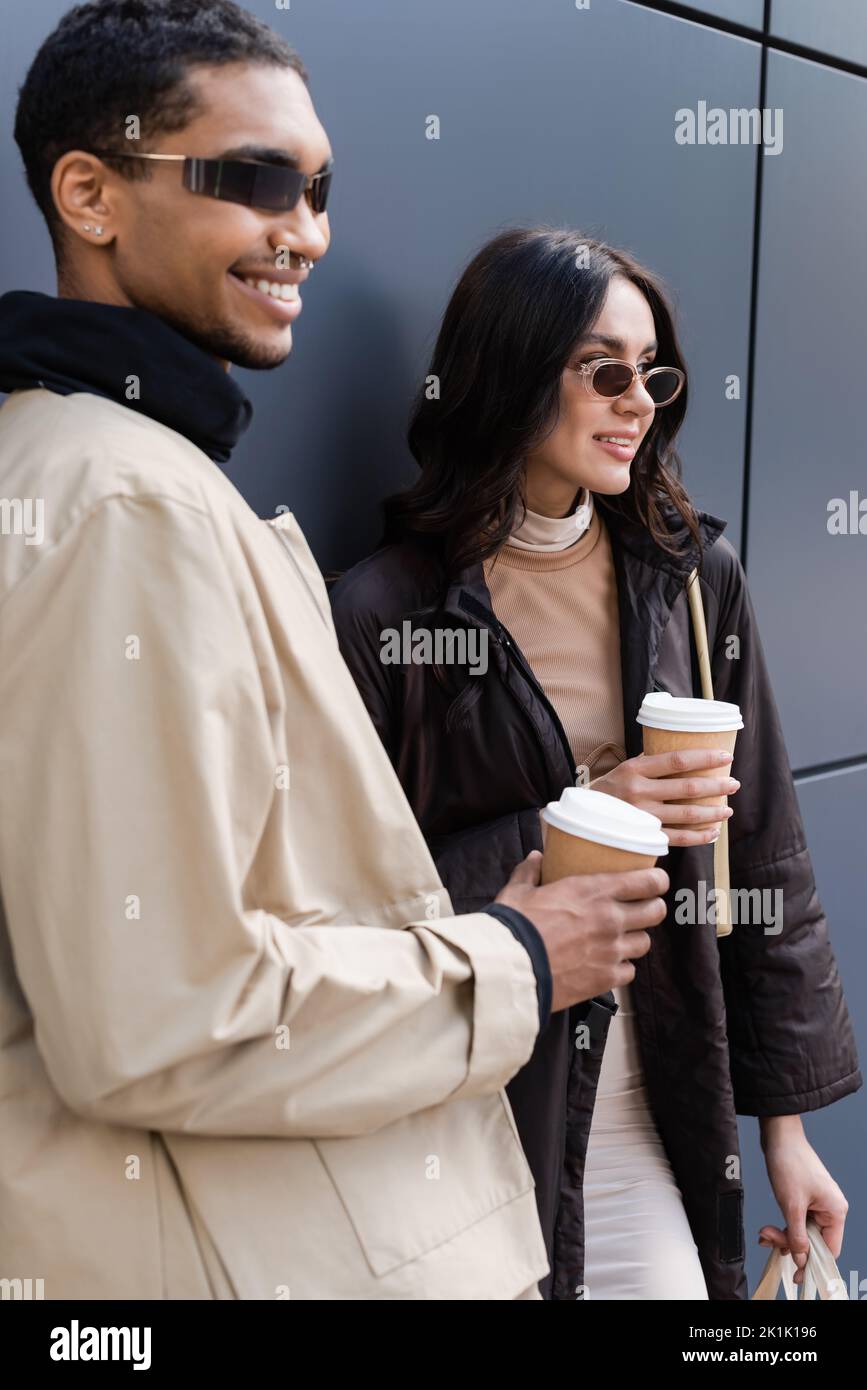 happy african american man and young woman in stylish sunglasses ...
