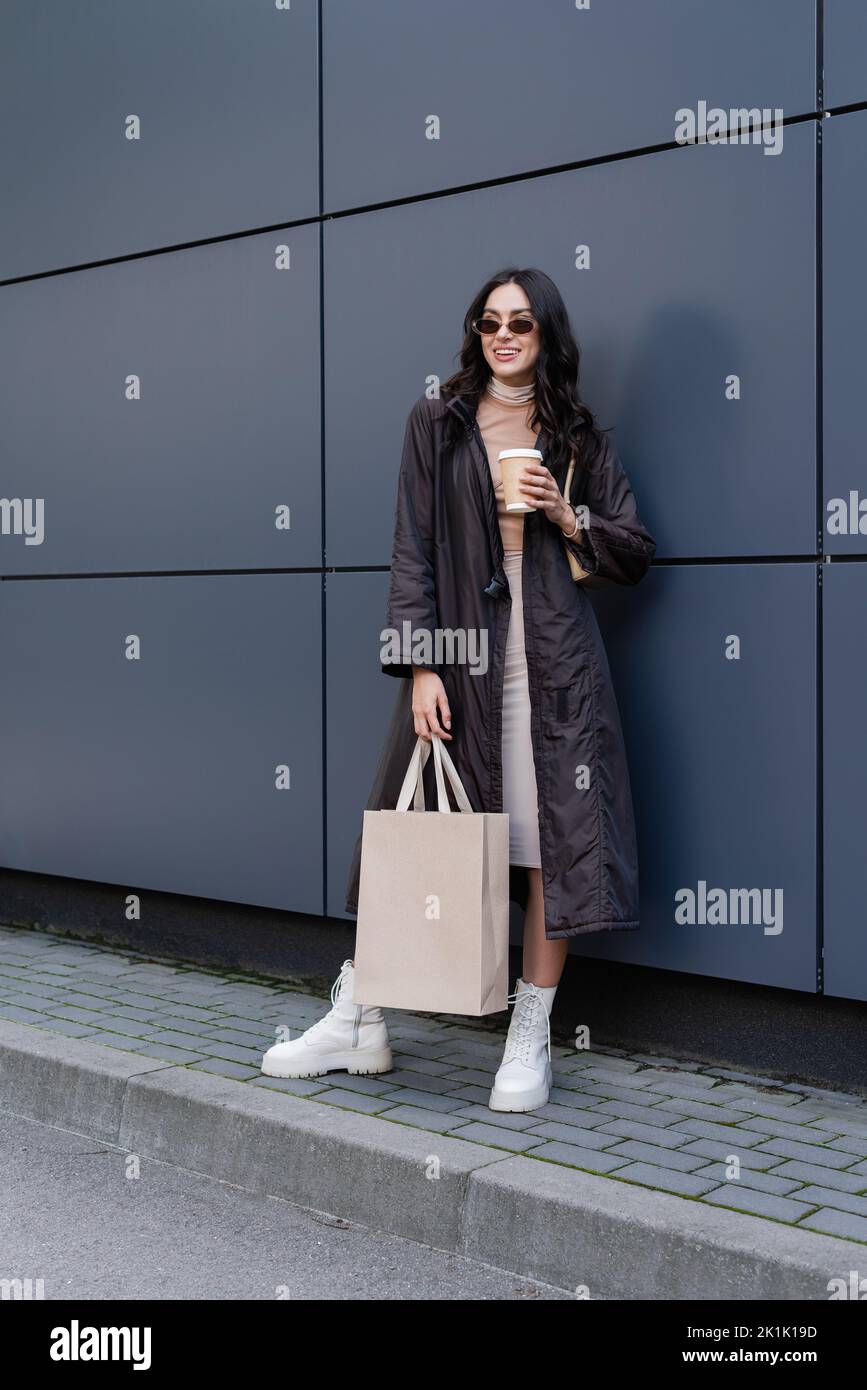 full length of happy young woman in stylish outfit and sunglasses ...