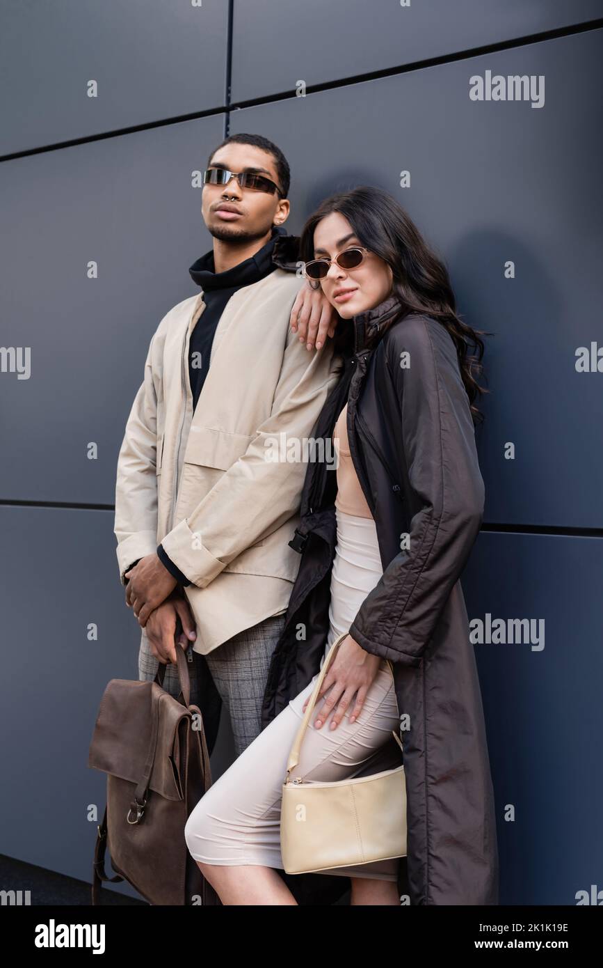 african american man in sunglasses holding leather backpack near ...