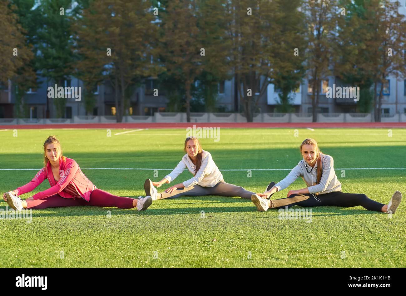 Three girls doing stretching exercises at the football stadium Stock ...