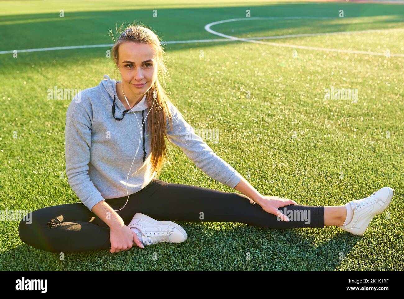 Sports girl doing stretching on the stadium lawn Stock Photo - Alamy