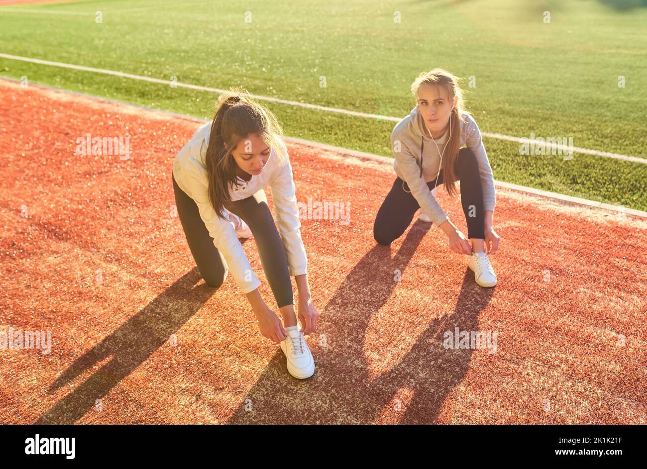 Two girls in sportswear are preparing to run on the running track ...