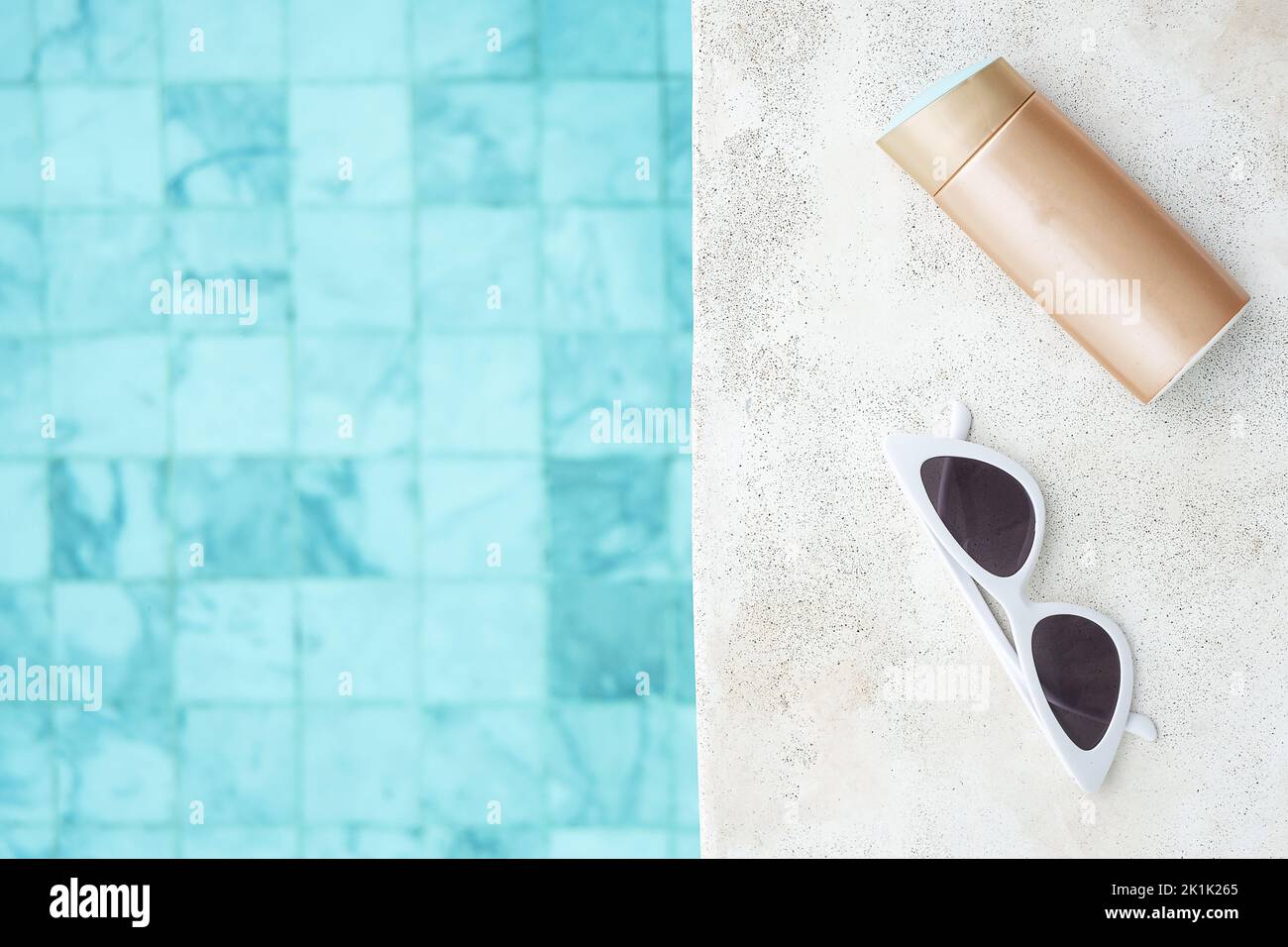 white sunglasses, sunscreen bottle and hat near swimming pool in luxury ...