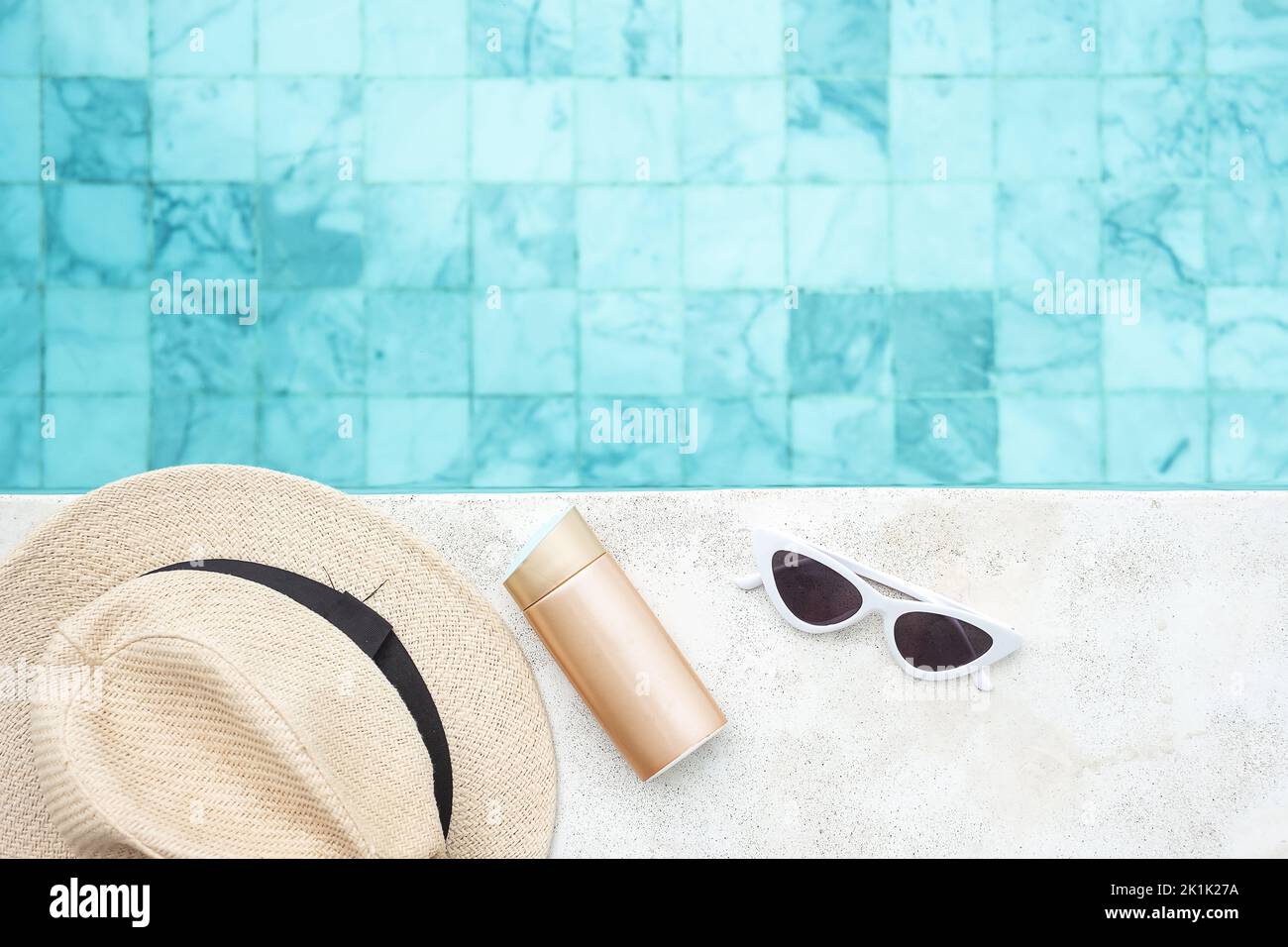 white sunglasses, sunscreen bottle and hat near swimming pool in luxury ...