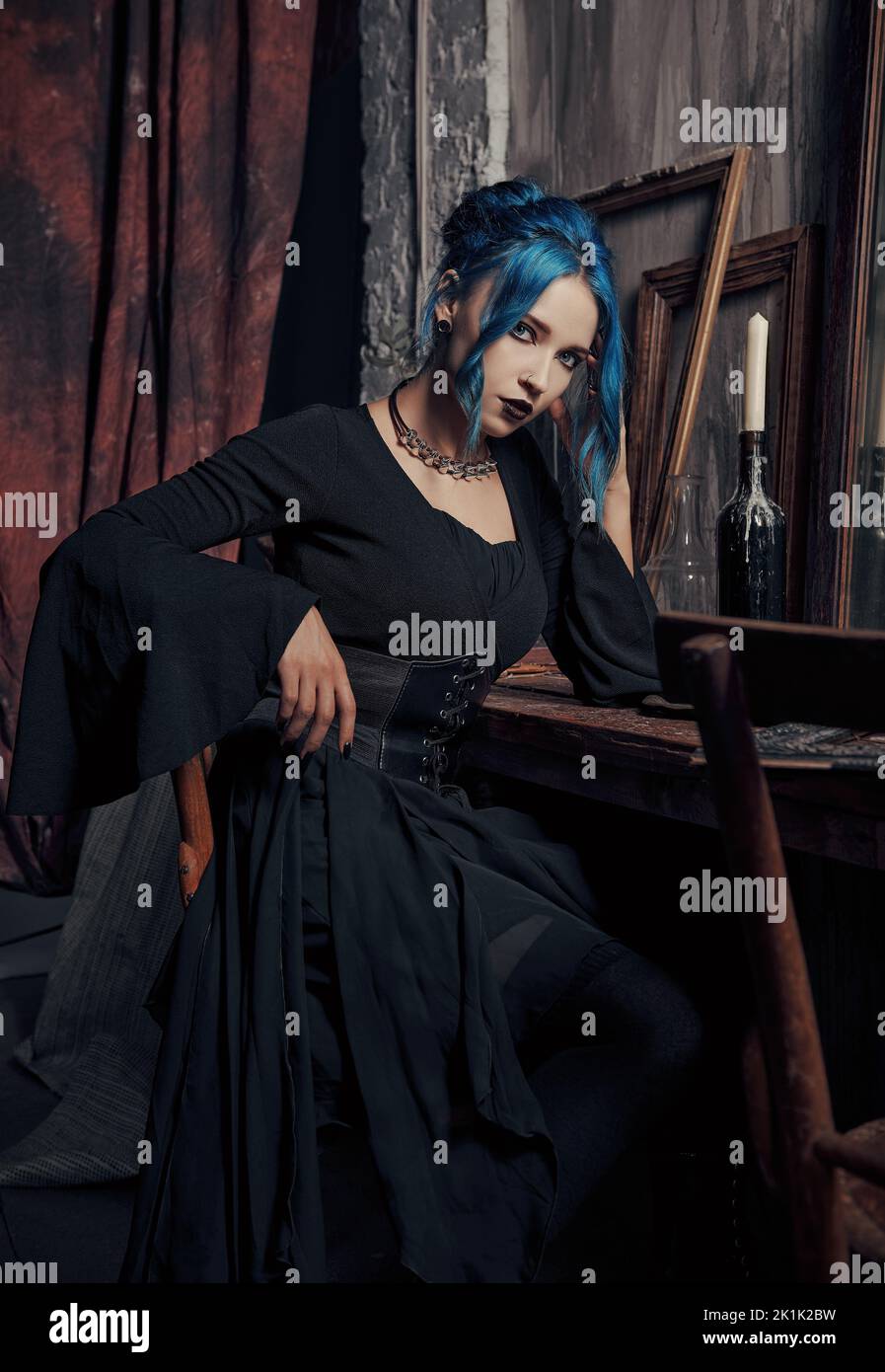 Indoors portrait of lovely goth girl in black dress. Blue-haired gothic ...