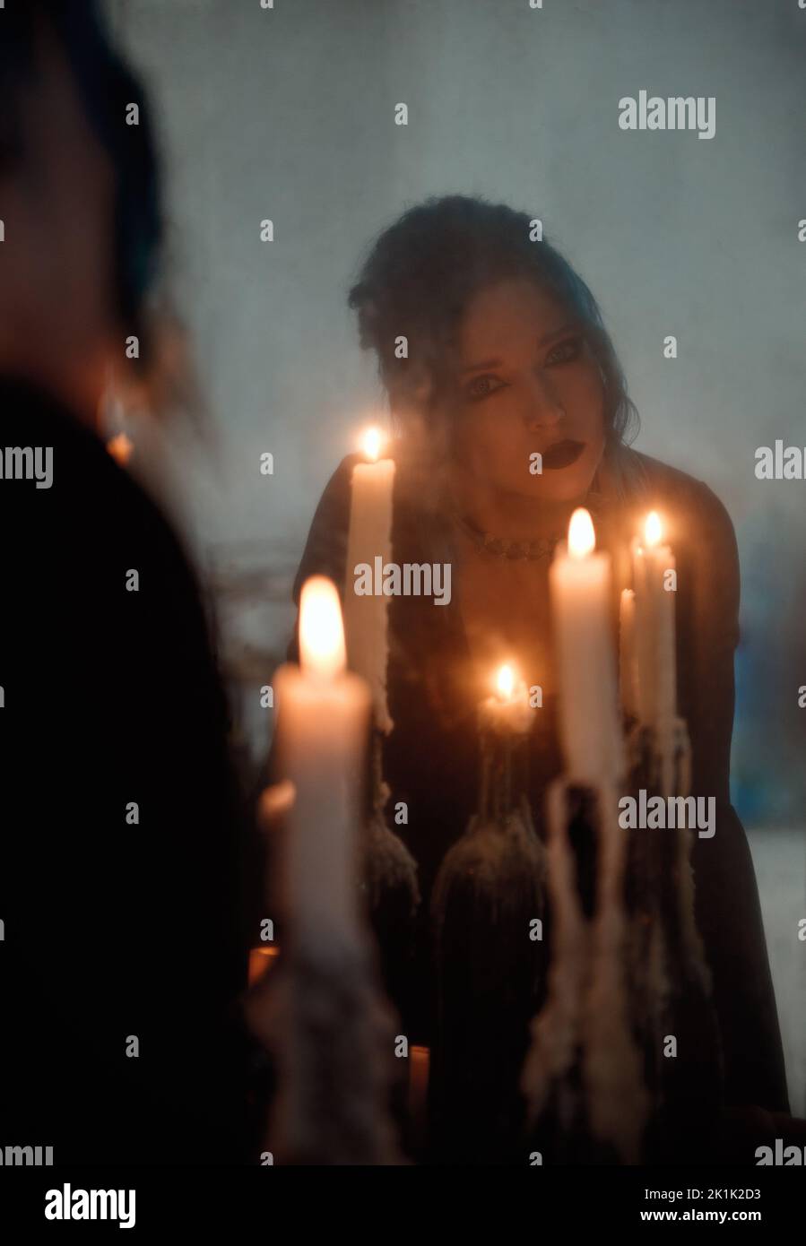 Indoors portrait of sad goth girl among candles. Blue-haired gothic ...