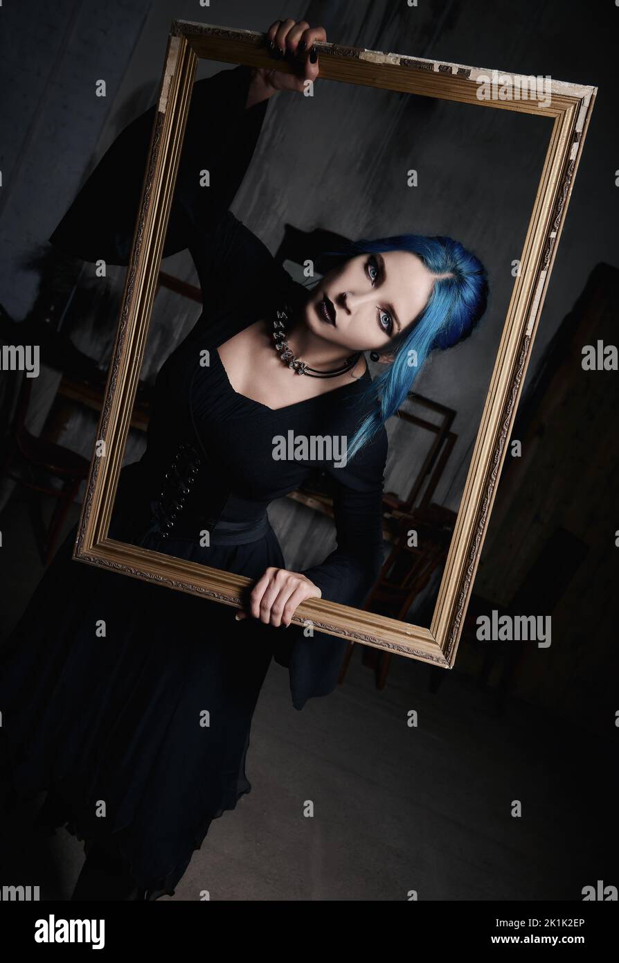 Indoors portrait of lovely goth girl in black dress. Blue-haired gothic ...