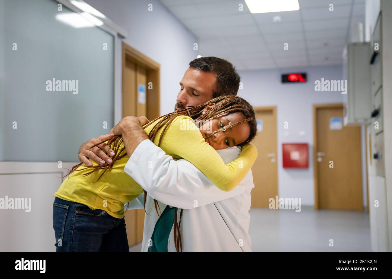 Male doctor consoling little girl after bad news in hospital ...