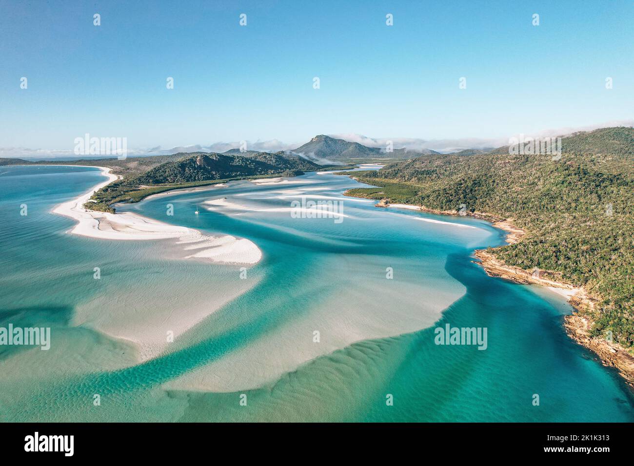 Blue ocean hues and soft white sand surrounded by lush green jungle. An ...