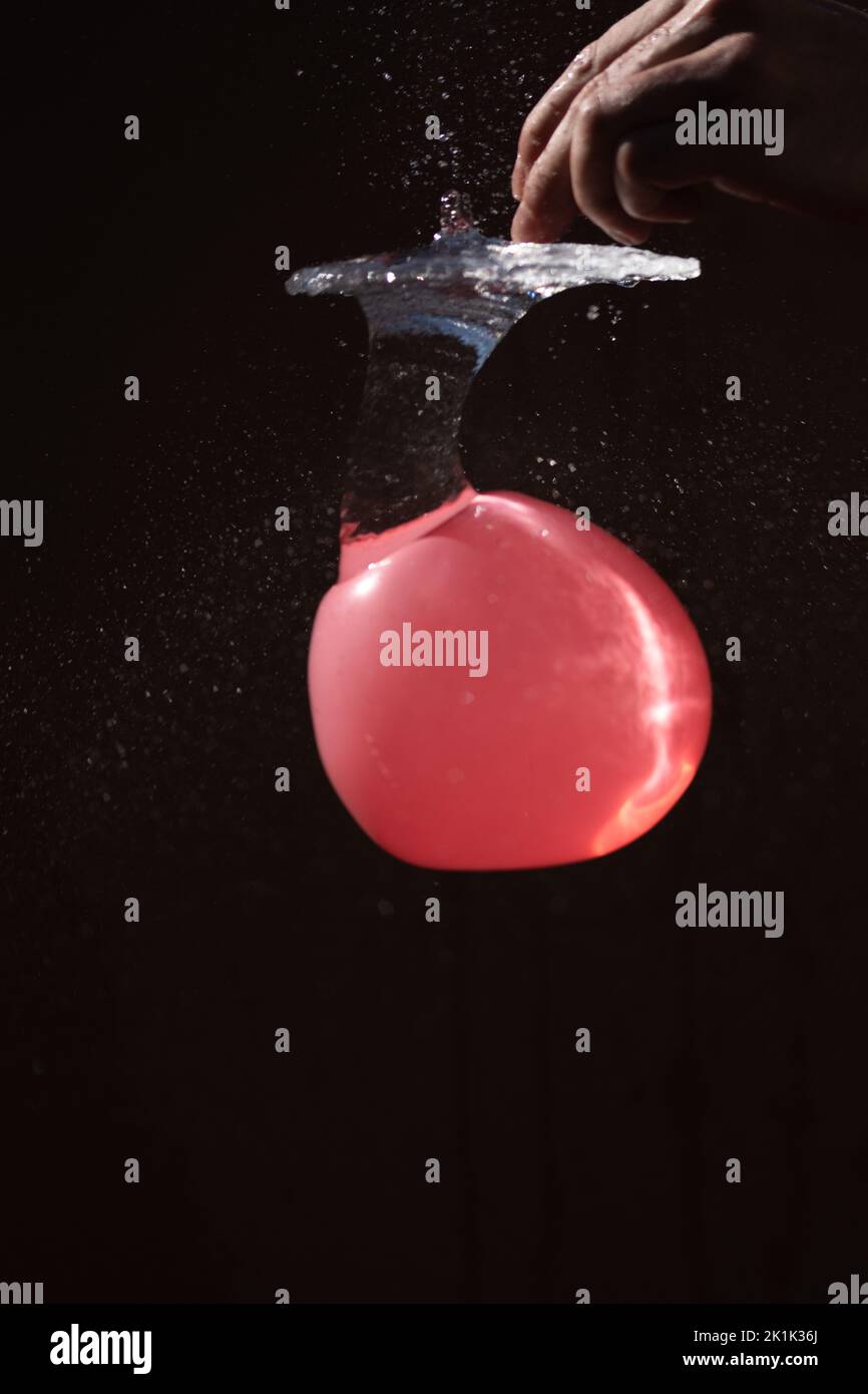 balloon filled with water is punctured and the exploding water takes ...