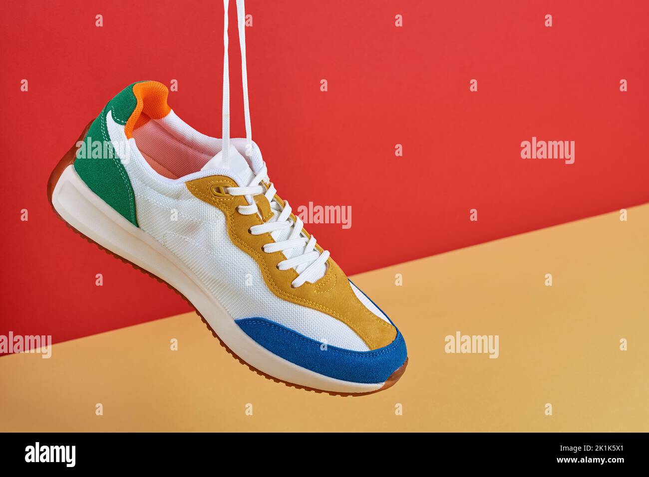 Hanging fashionable sneakers on colorful background. Stylish sports ...