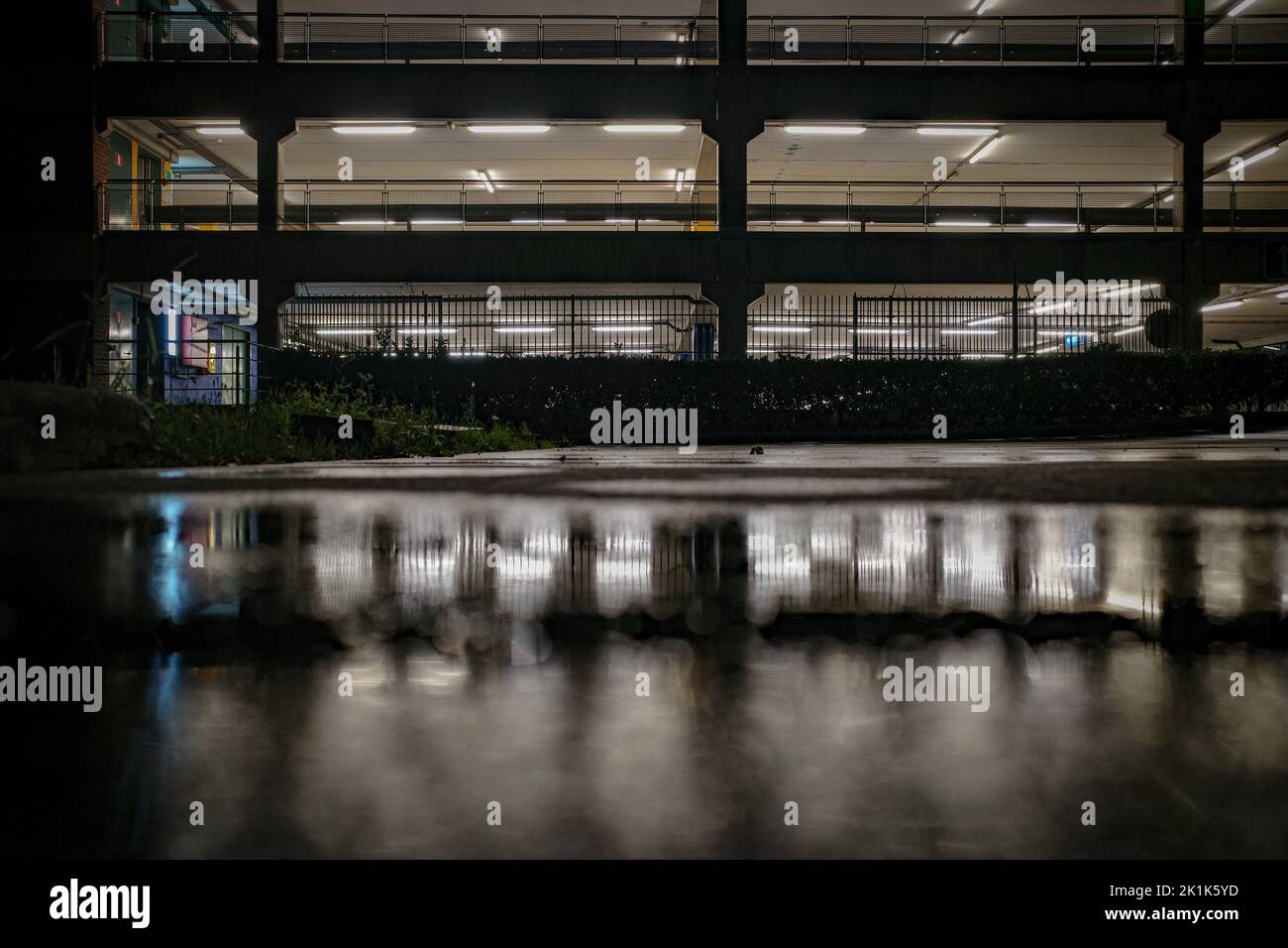 Reflected view in rain puddle of empty parking space of shopping mall ...