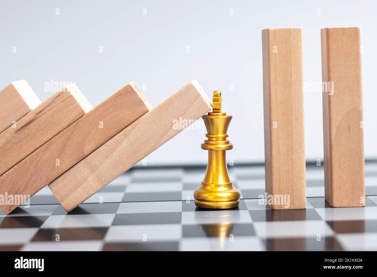 wooden Blocks or Dominoes falling to golden Chess King figure. Business ...