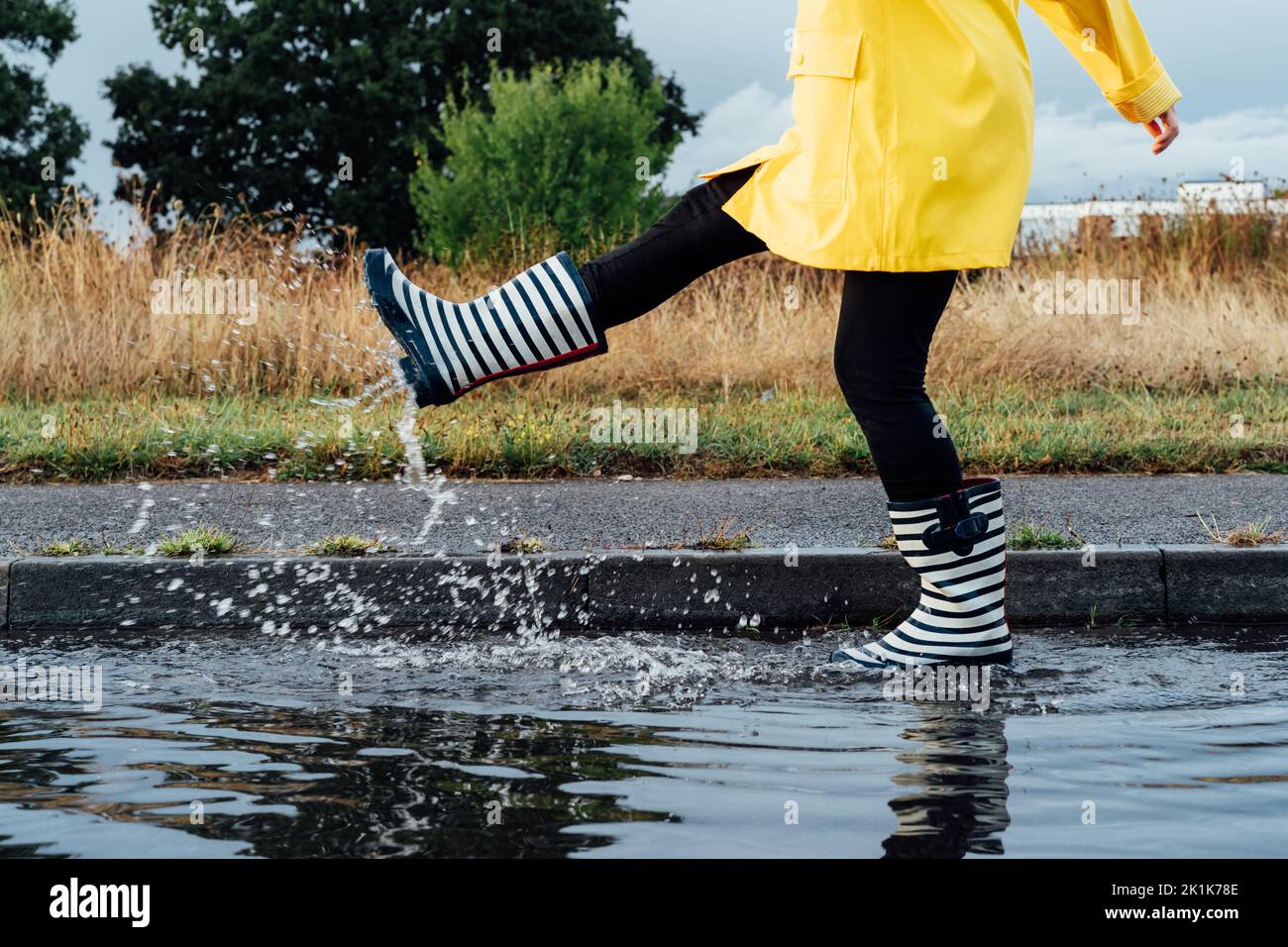 Woman having fun on the street after the rain. Cropped woman wearing ...