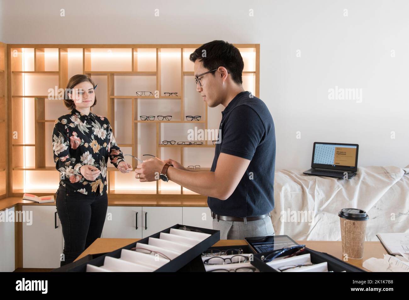 Optometry shop owners arranging eyeglasses a display, preparing for ...