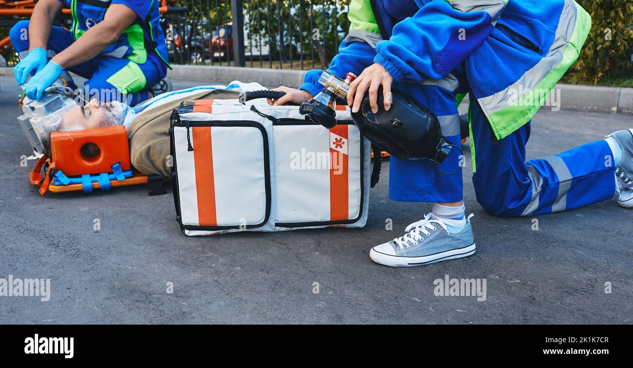 Emergency doctor taking manual resuscitation bag to unconscious male ...