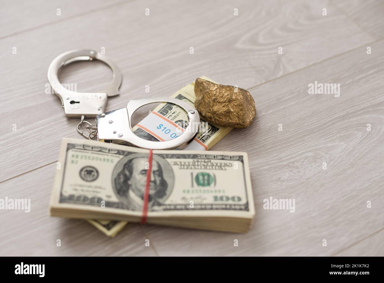 Police handcuffs lie on many dollar bills isolated on black background ...