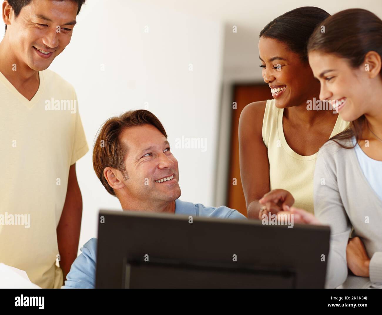 Keeping them motivated. a work team gathered around a computer Stock ...