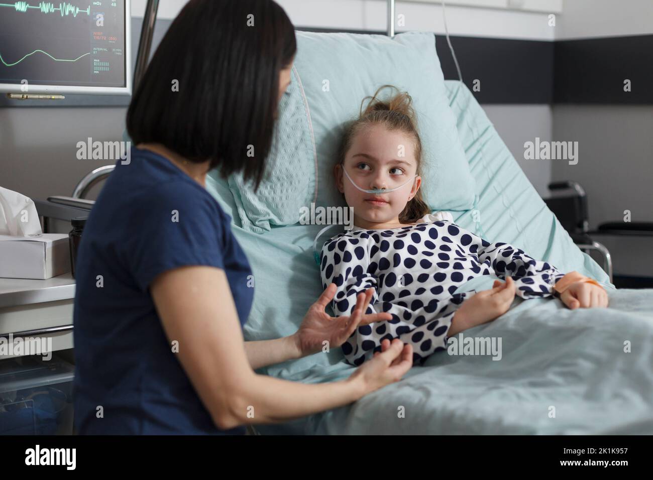 Caring mother talking with hospitalized ill daughter resting in ...