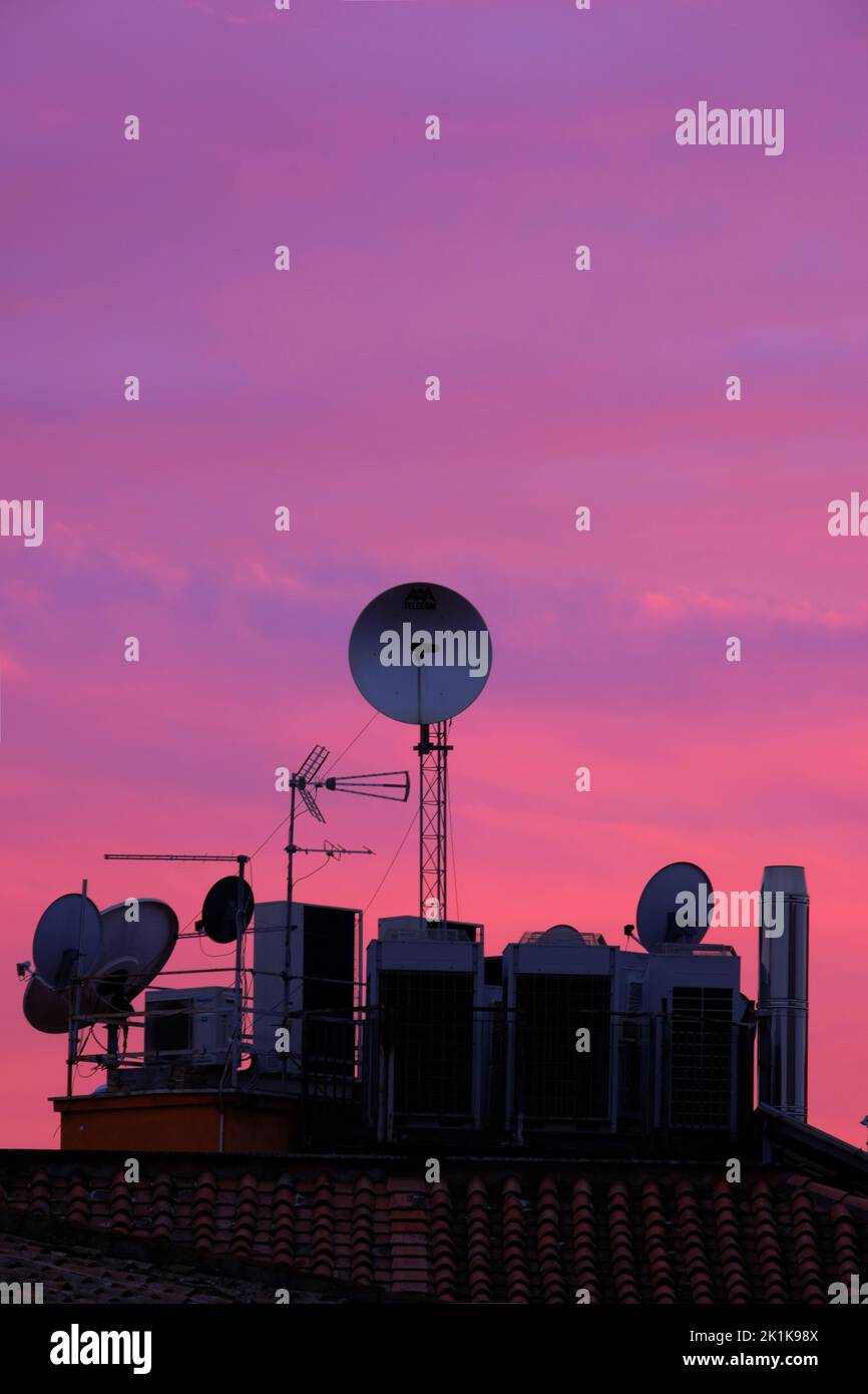 A vertical shot of a satellite antenna on a house roof with a purple ...