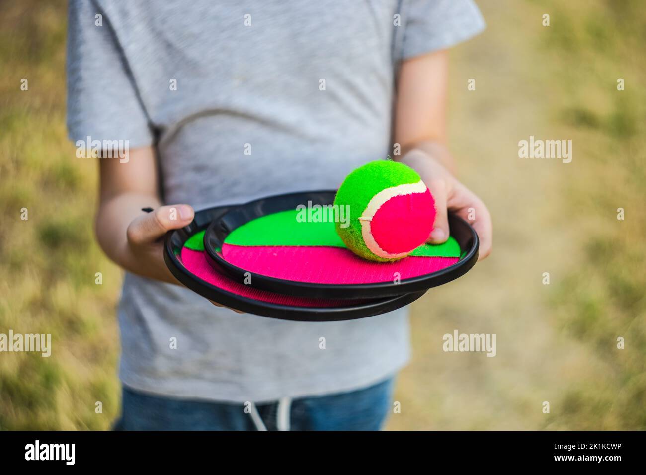 Close-up of a boy standing a park holding a velcro sticky ball game ...