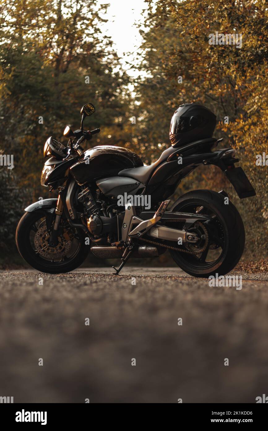 A vertical shot of a black motorcycle and helmet standing outdoors with ...