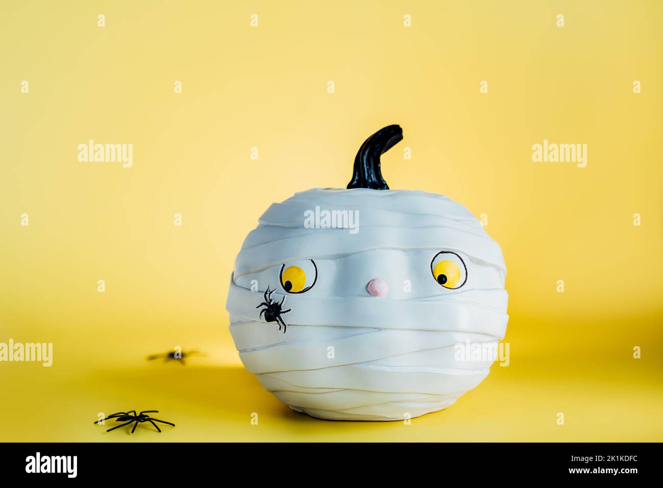 Funny and cute pumpkin mummy with spider on the yellow background ...