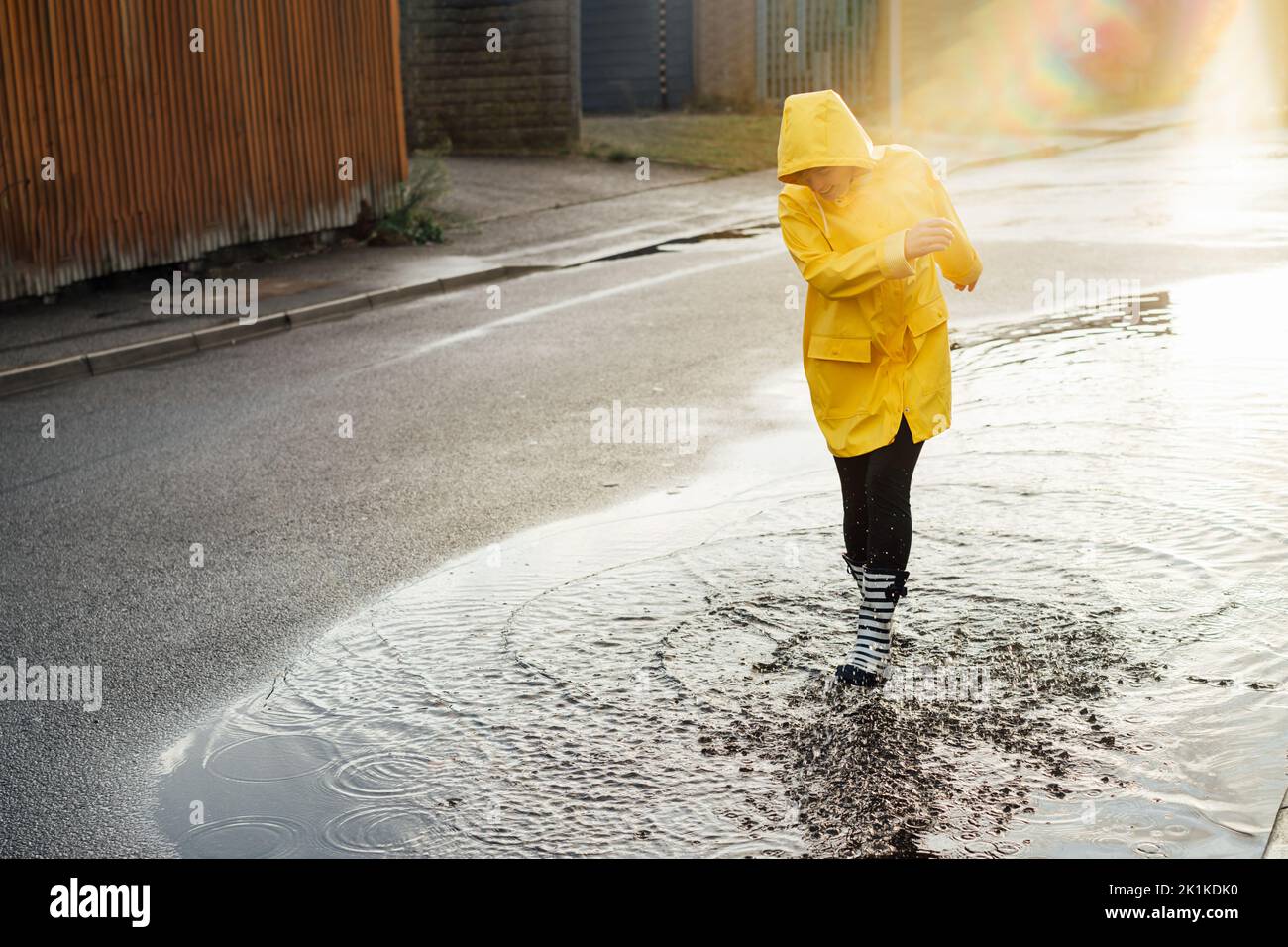 Woman having fun on the street after the rain. Smiling woman wearing ...