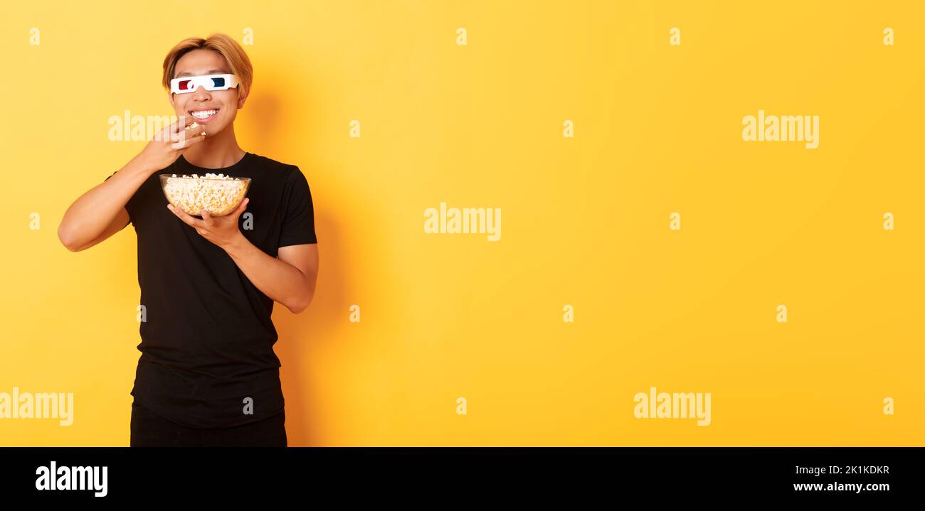 Joyful handsome asian guy with blond hair, watching movie or tv series ...