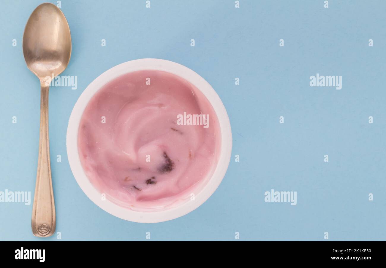 Yogurt cup with pink strawberry yoghurt isolated on baby blue ...