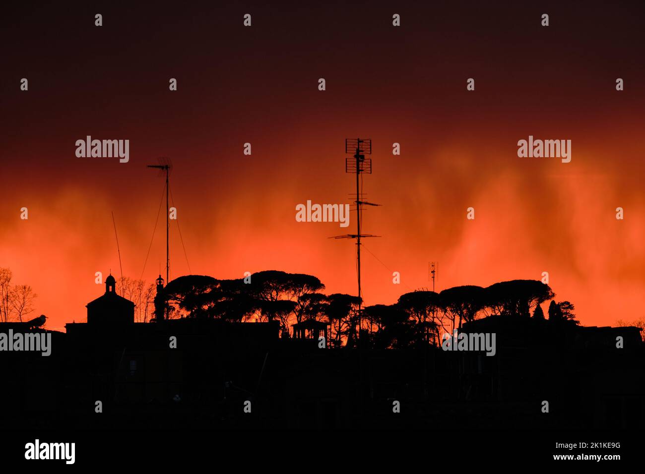 Different silhouettes of a church and trees against dramatic red sunset ...