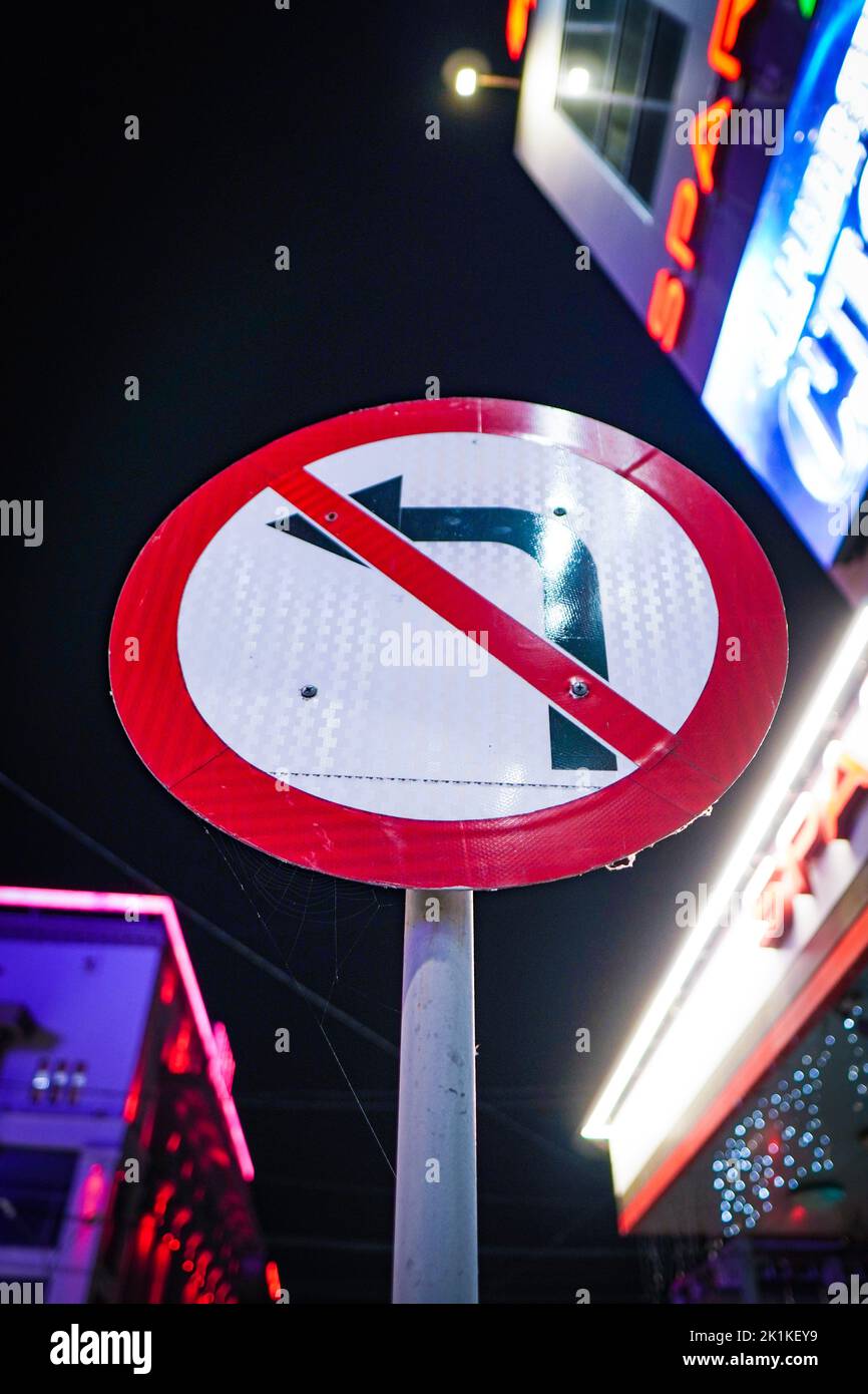 The vertical low-angle view of the no-left turn sign against the night ...
